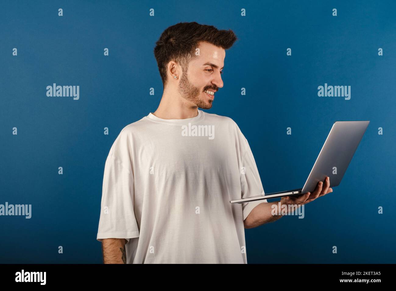 Happy young man wearing white t-shirt posing isolated over blue ...