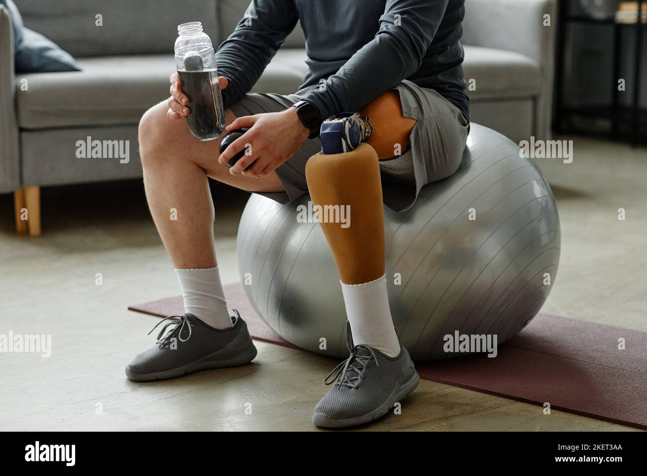 Close up of unrecognizable man with prosthetic leg sitting on fitness ...
