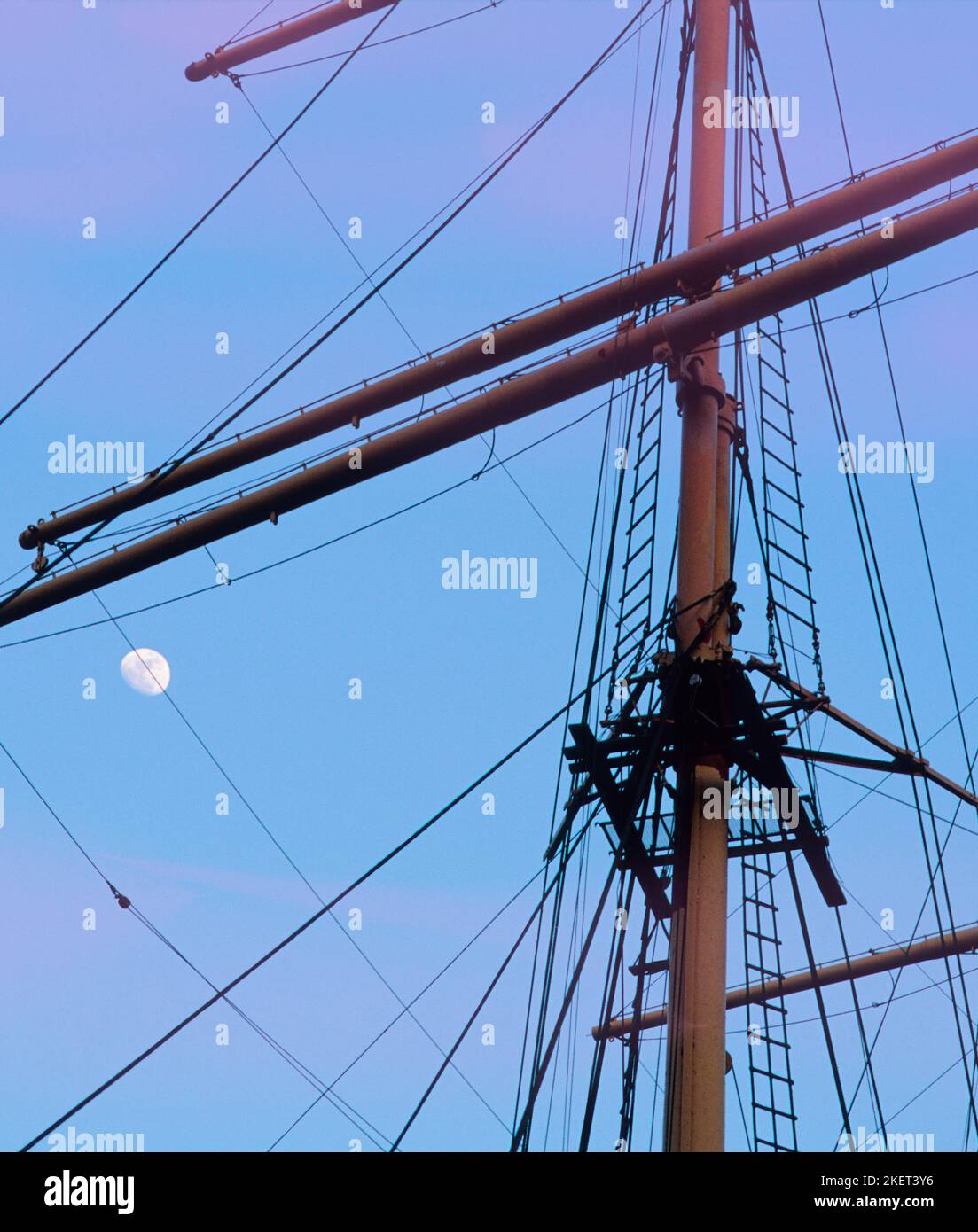 Ship in port. Mast with sails down at night in harbor. Moon. No people ...