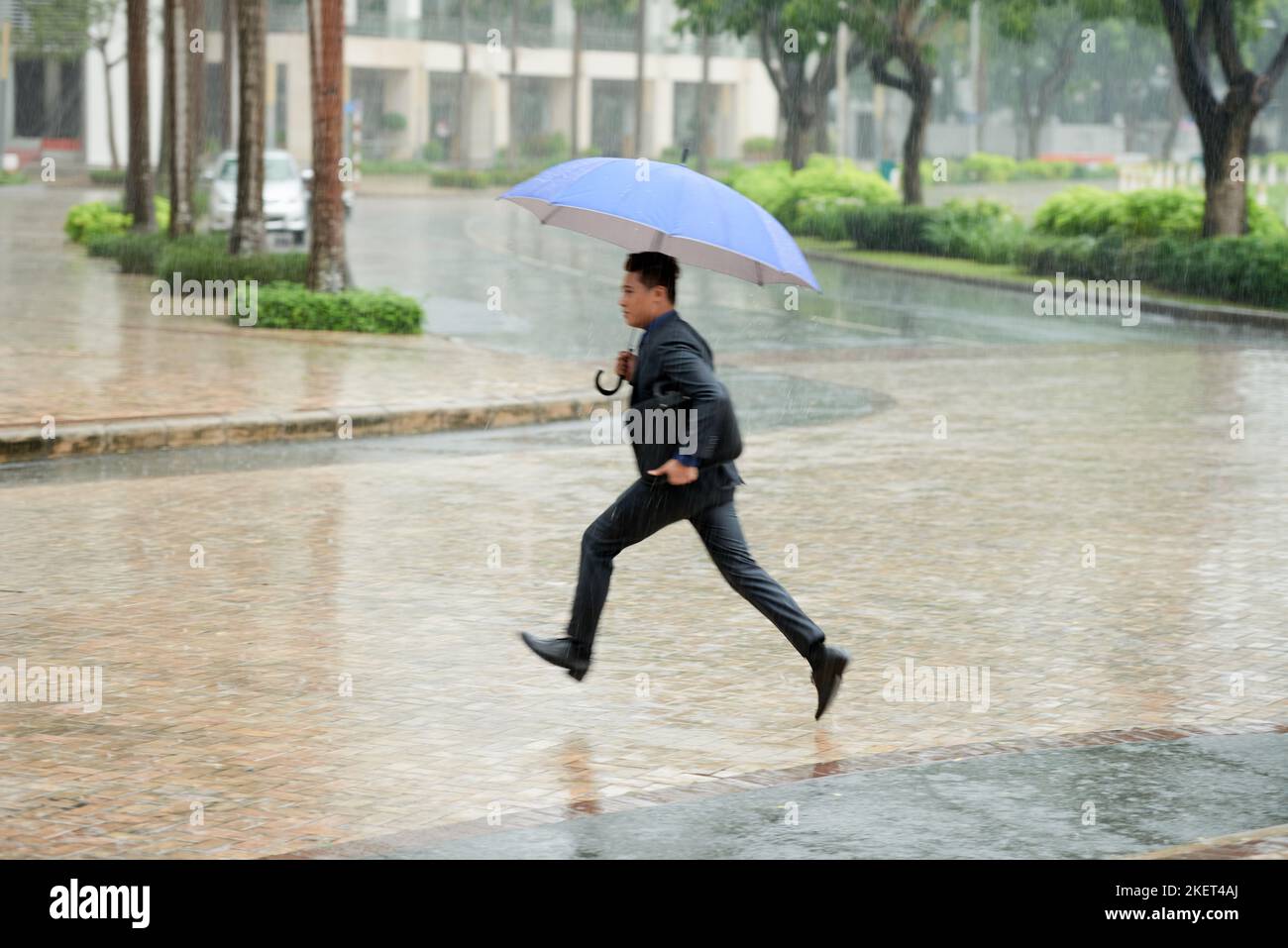 Young Vietnamese businessman wearing classical suit crossing road while ...