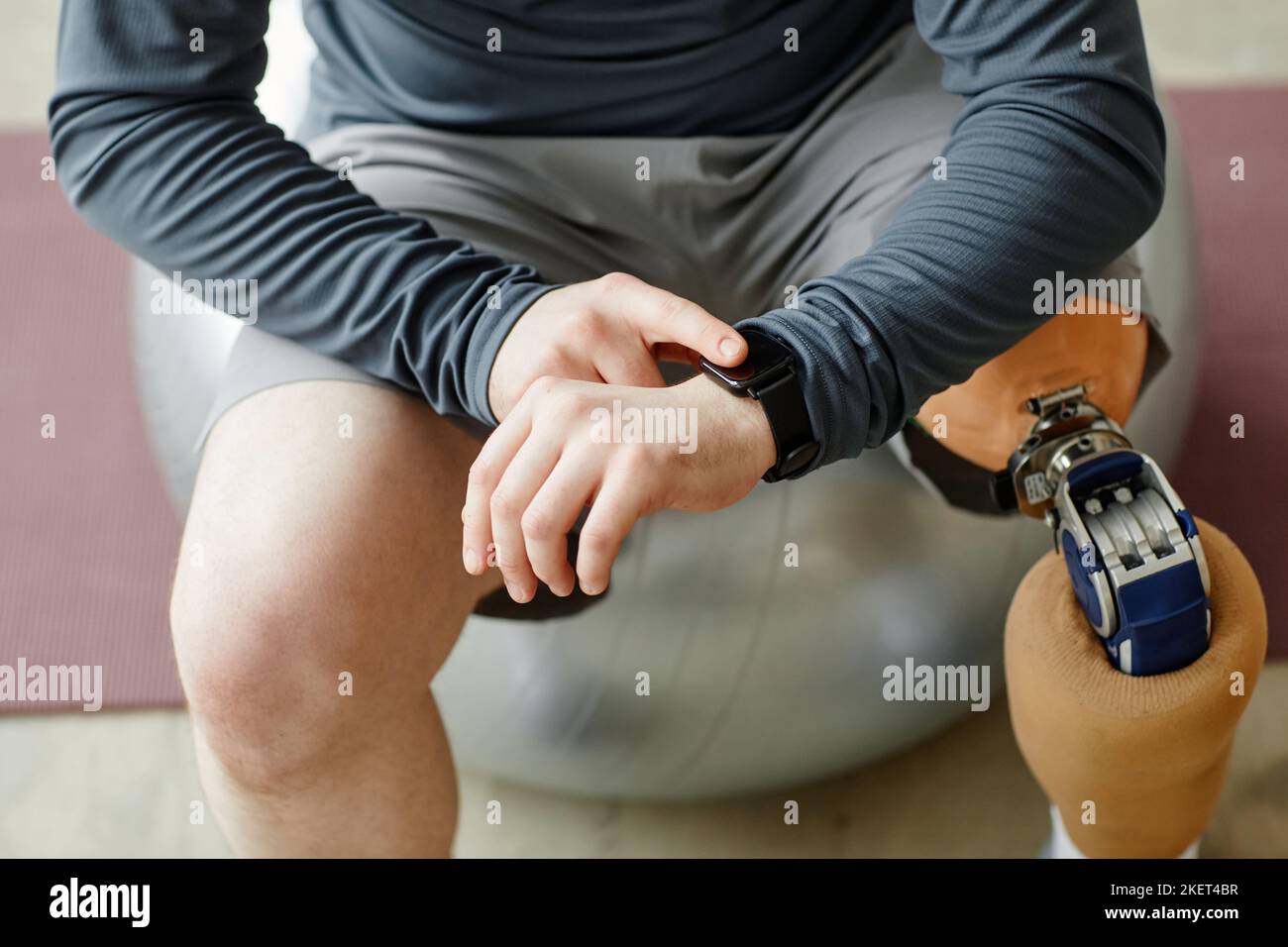 Close up of man with prosthetic leg checking smartwatch sitting on ...