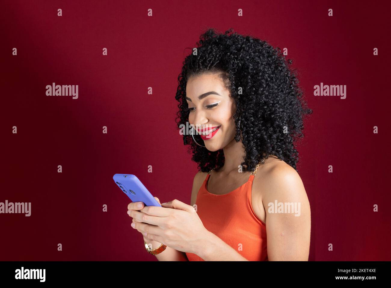 Young beautiful, cheerful woman looking at her cell phone. wearing ...