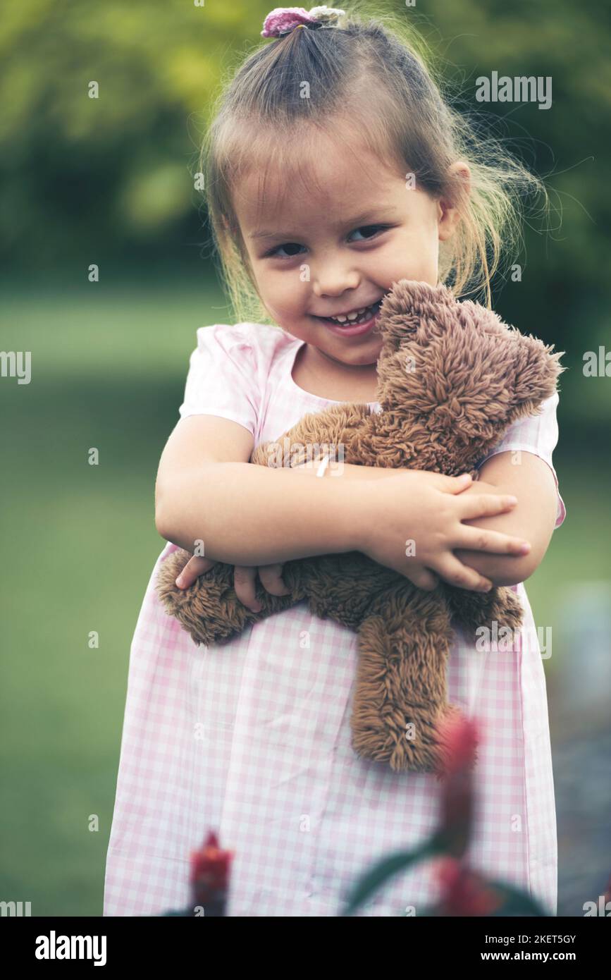 Smiling little girl hugging her teddy bear Stock Photo - Alamy