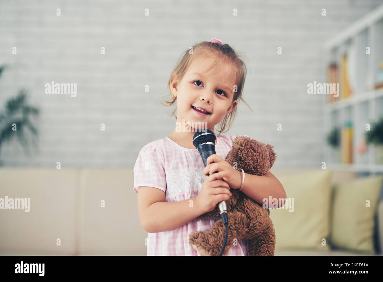 Portrait of smiling little girl singing a song in microphone Stock ...