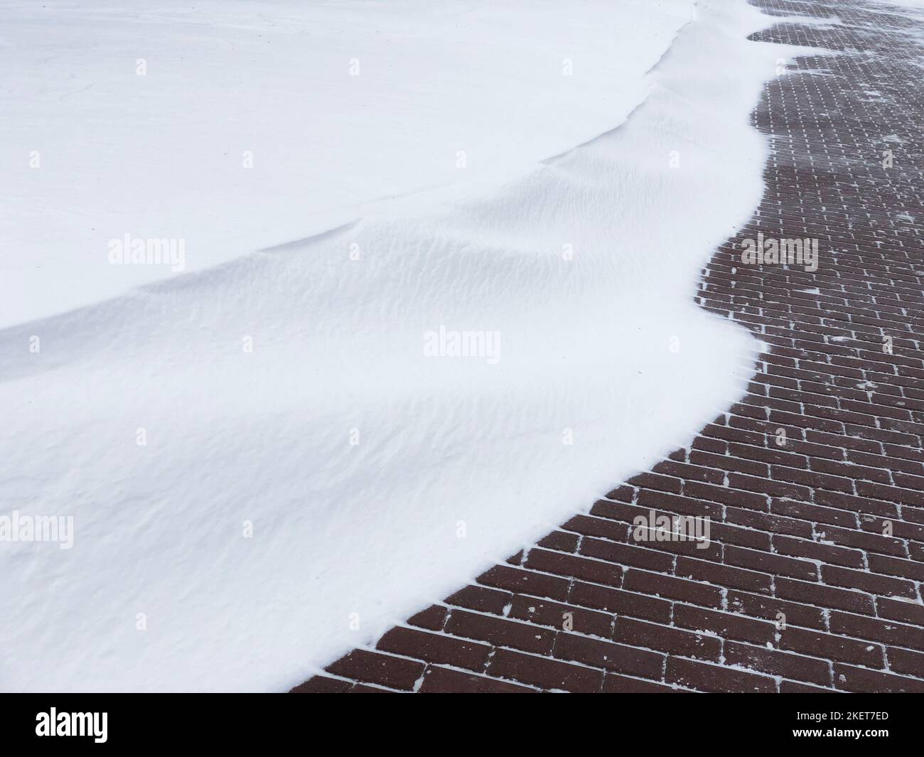 Snow drift with red brick wall in background Stock Photo - Alamy