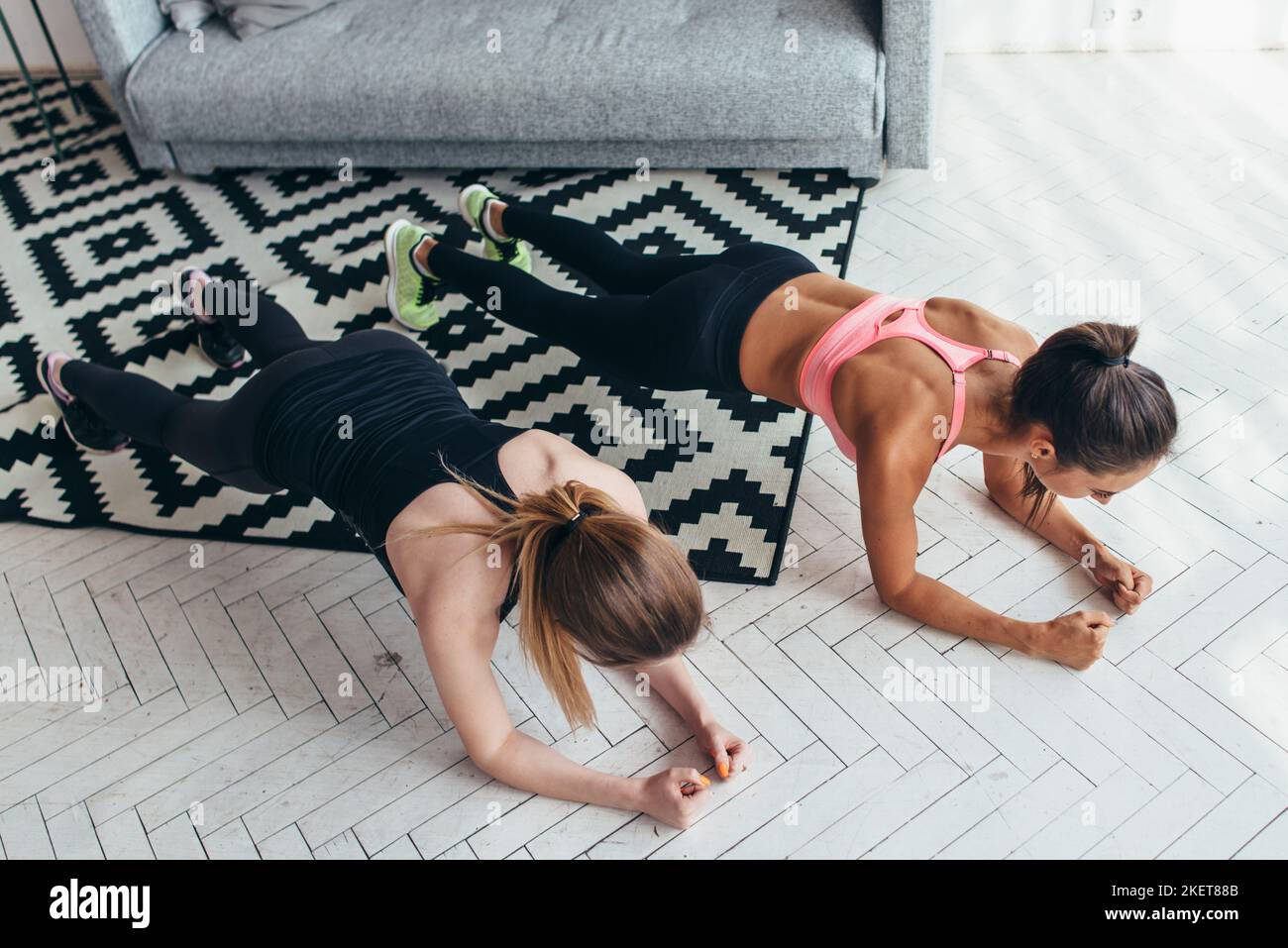 Two fit women standing in plank position on floor strengthening core ...