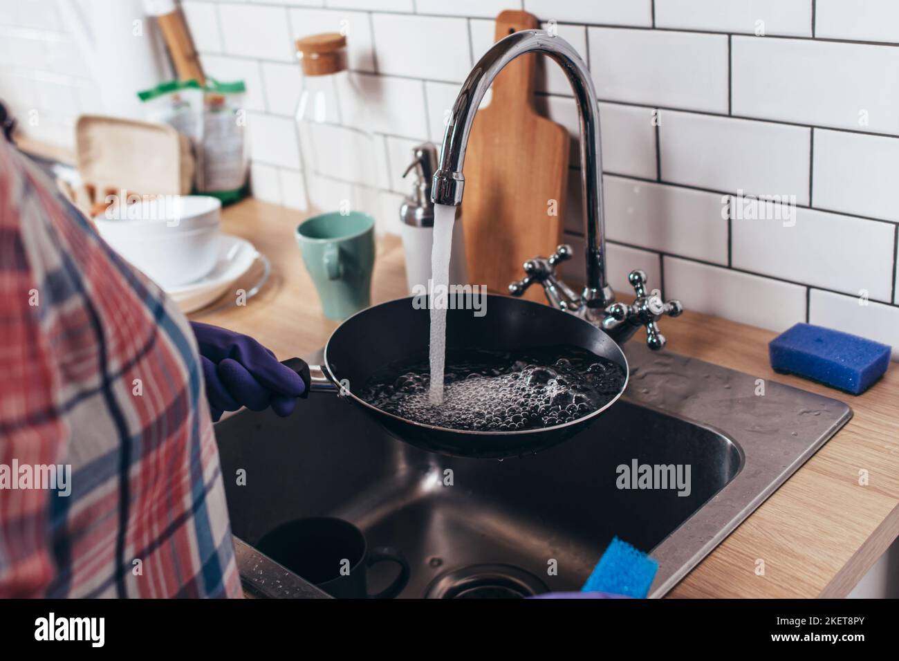Young woman wearing rubber gloves washing frying pan in kitchen Stock ...