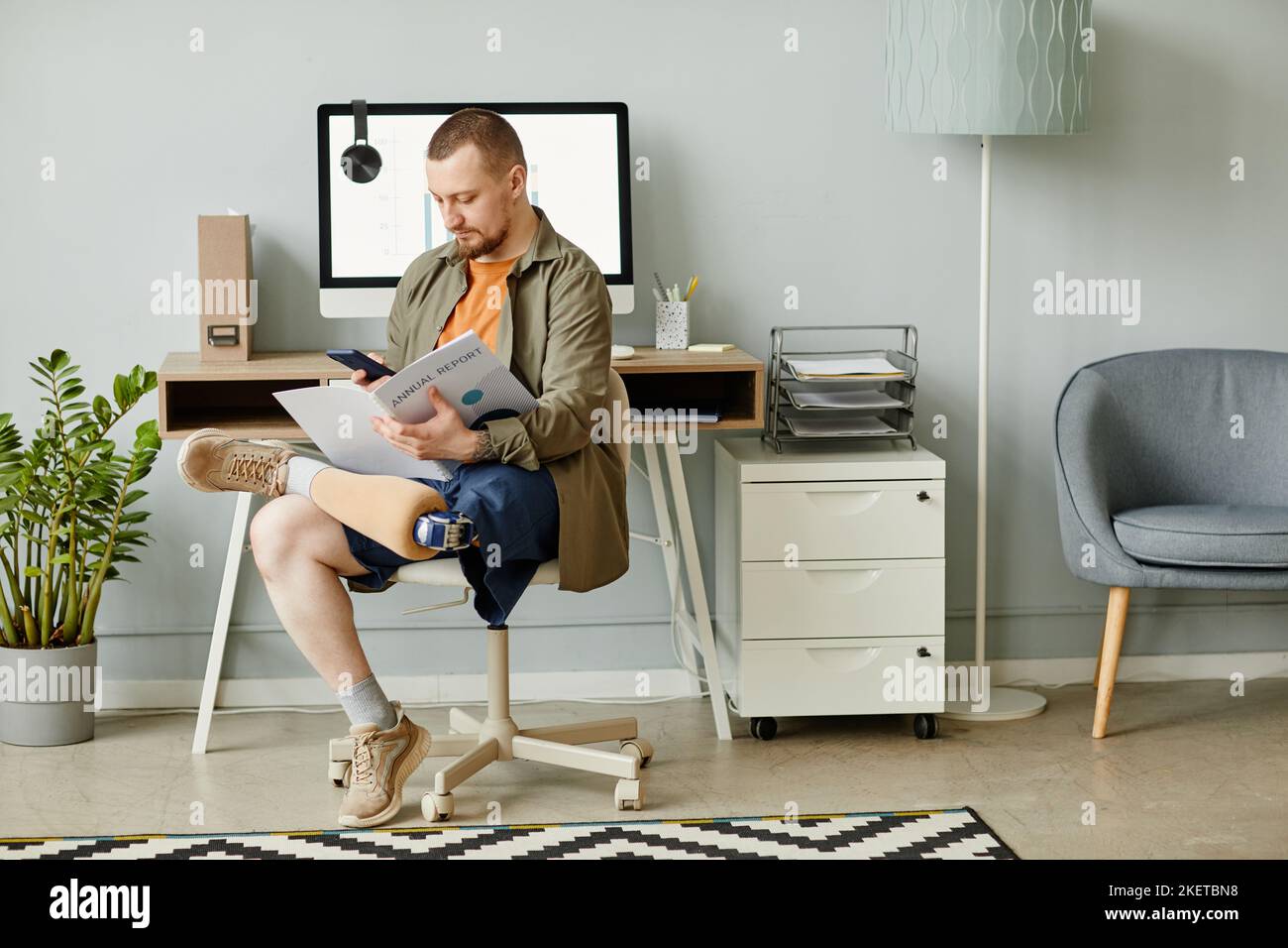 Full length portrait of man with prosthetic leg reading document at ...