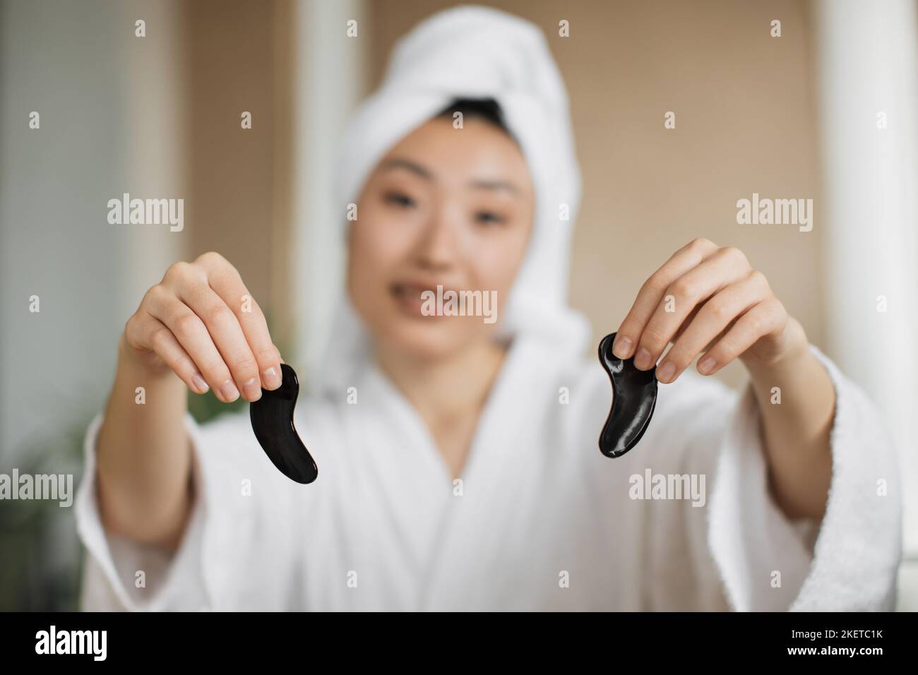 Focus on hands of pleasant asian woman in white bathrobe and towel ...