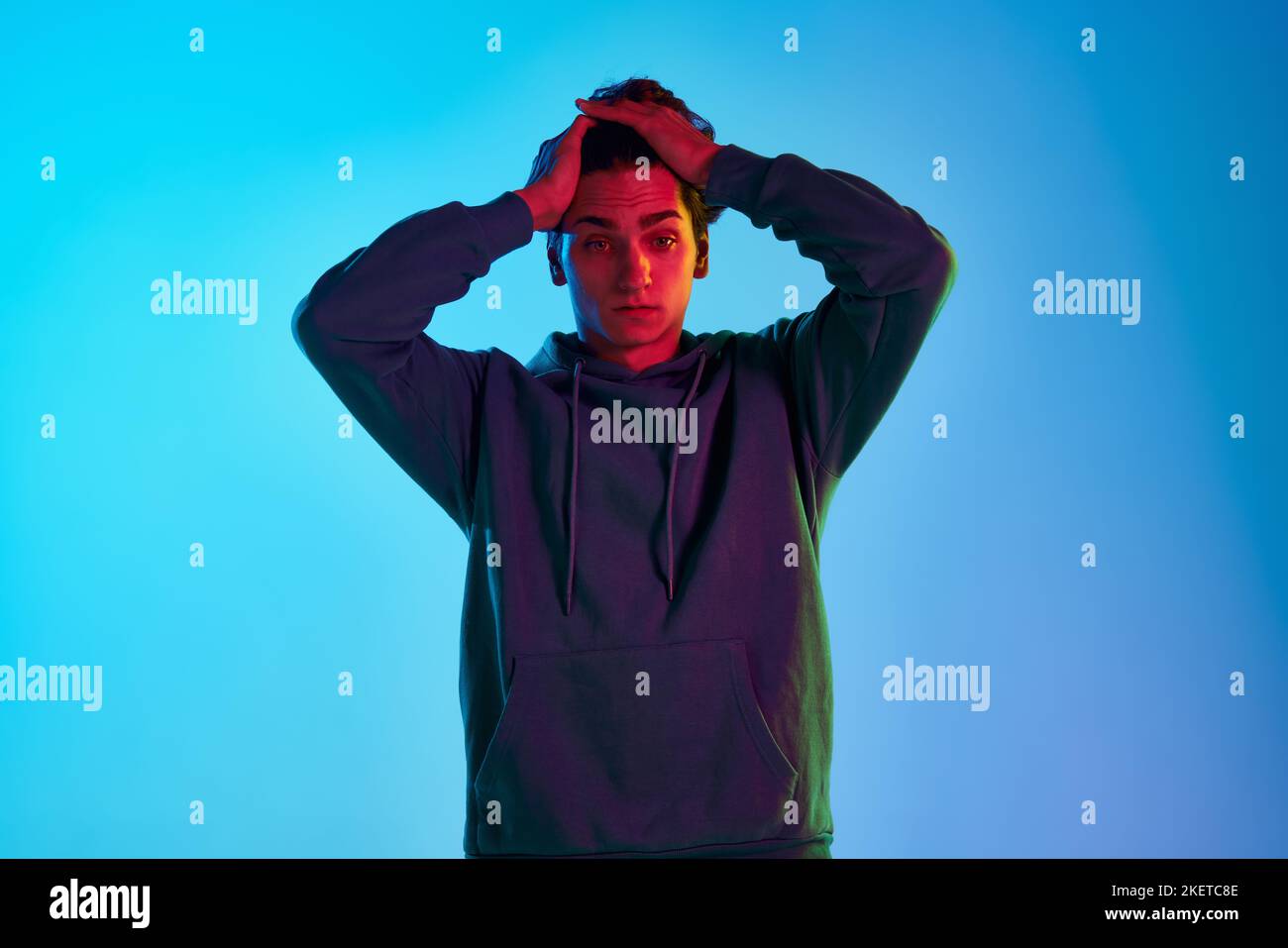 Portrait of young man with curly hair posing with shocked expression ...