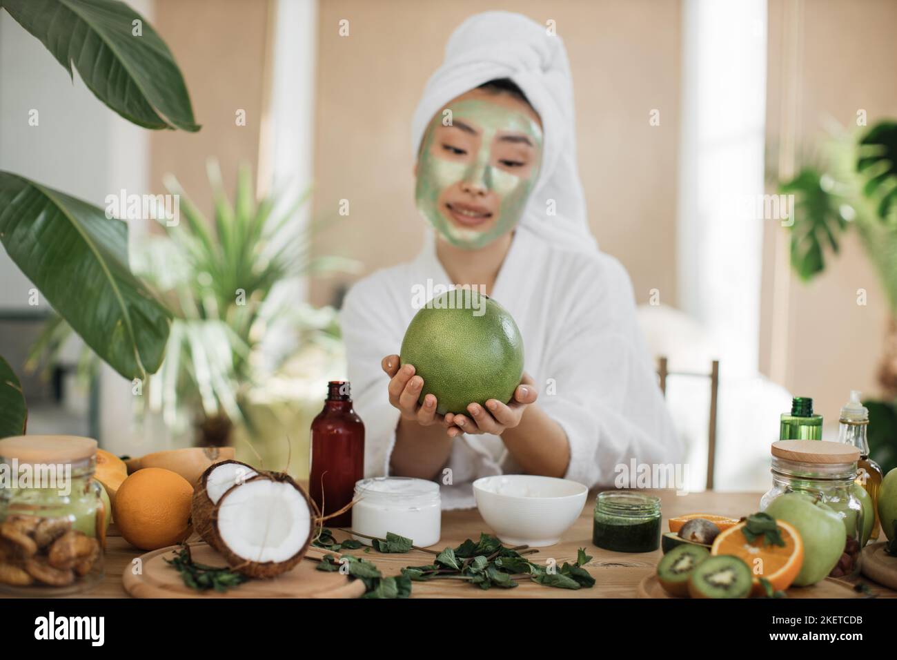 Focus on hands of beautiful young asian woman with green cosmetic mask ...