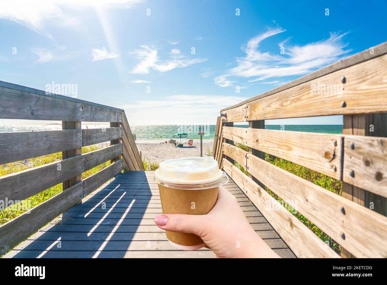 Indian rocks beach in Florida, USA with Hand holding paper cup of hot ...