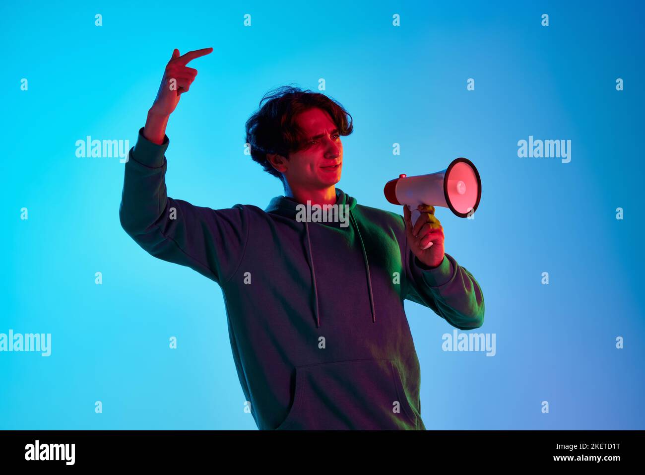 Portrait of young man with curly hair posing with megaphone isolated ...