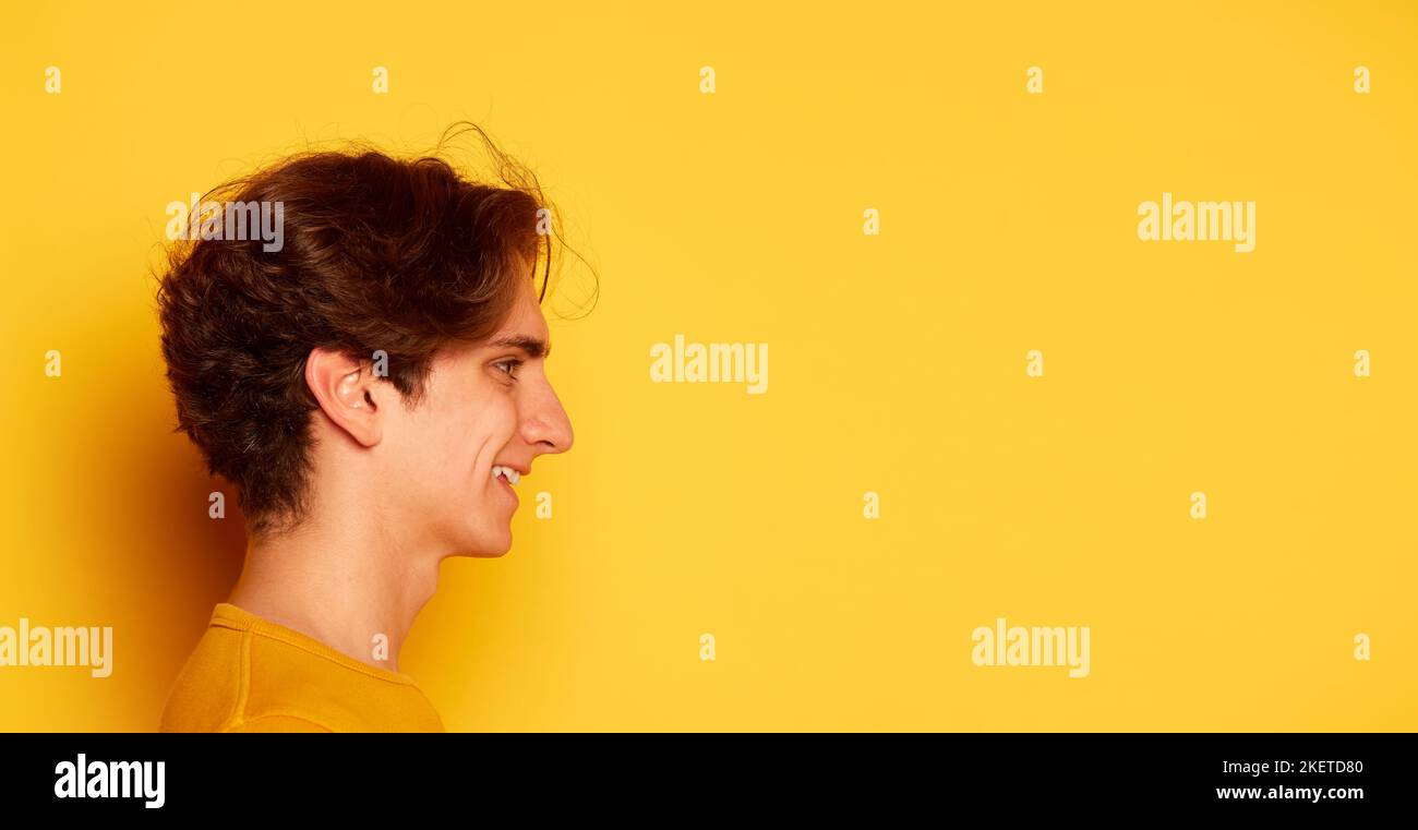 Side view portrait of young man with curly hair posing isolated over ...