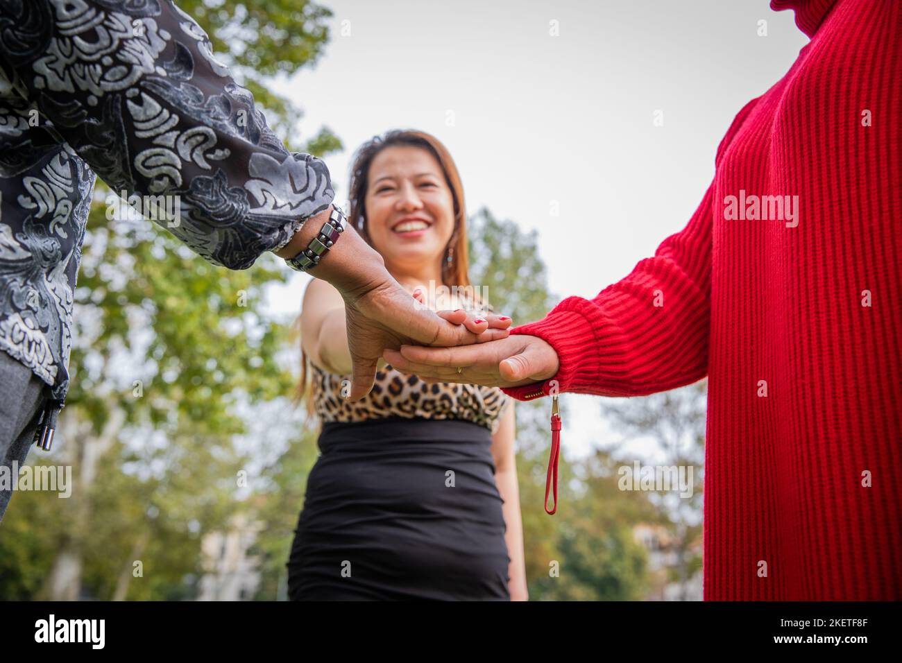 Three women of different ethnicities join hands as a sign of unity and ...