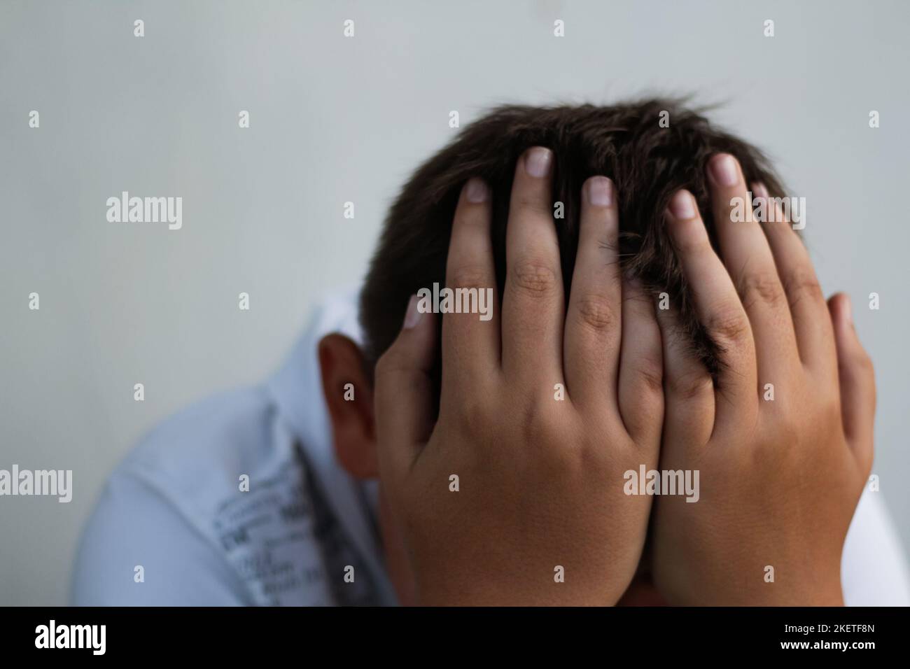 Defocus sad little boy sitting. Child cry and hiding his face. Kid ...