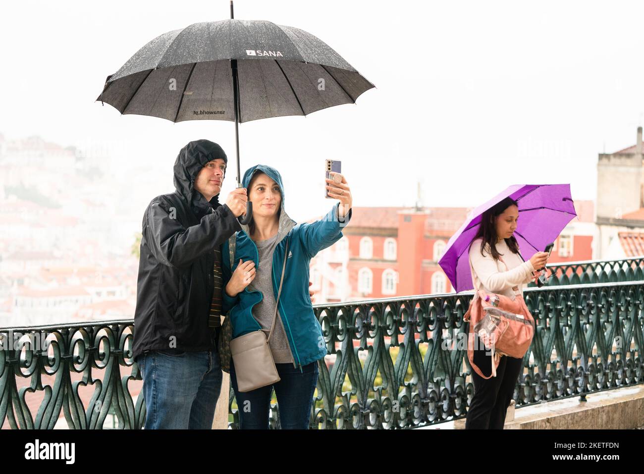 Heavy rain sweeps in and a couple take umbrella shelter for pictures ...