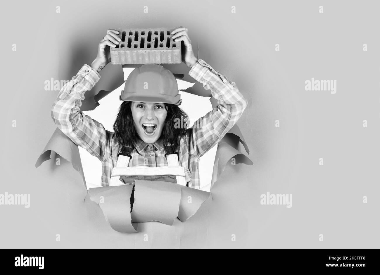 engineer hold brick. young female worker on blue background. repair and ...