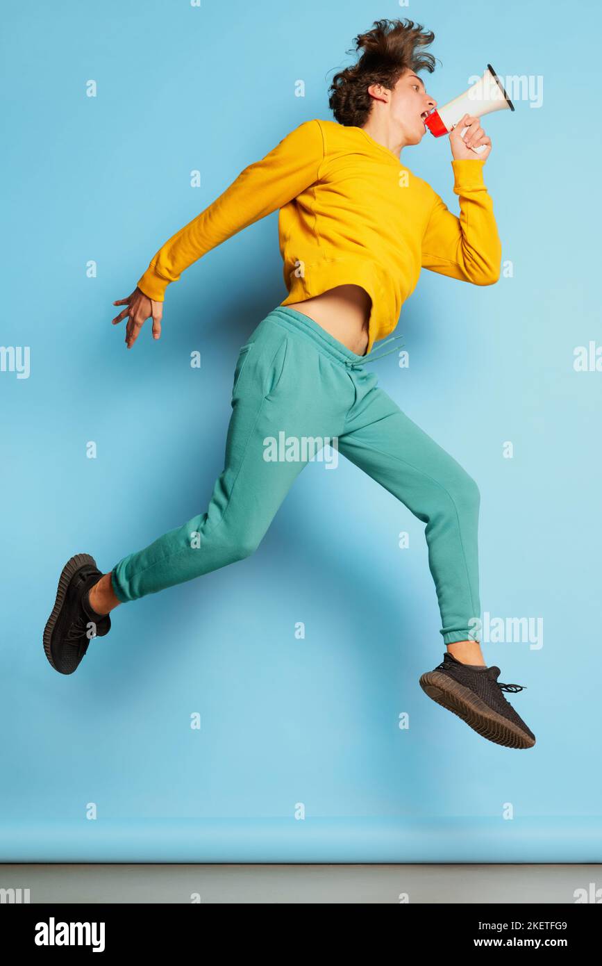 Portrait of young man with curly hair posing, jumping and talking in ...