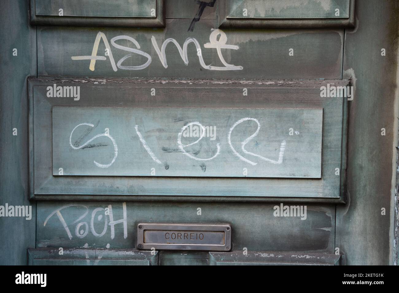 Names written in graffiti on an old faded door and postbox letterbox on ...