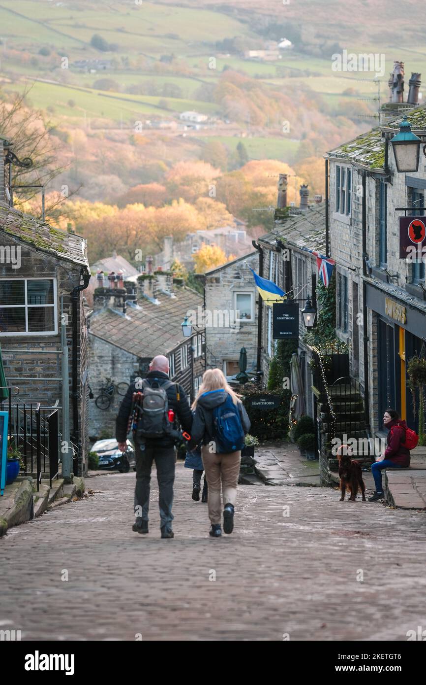 Haworth, West Yorkshire, UK. A couple walking down the cobbled Main ...