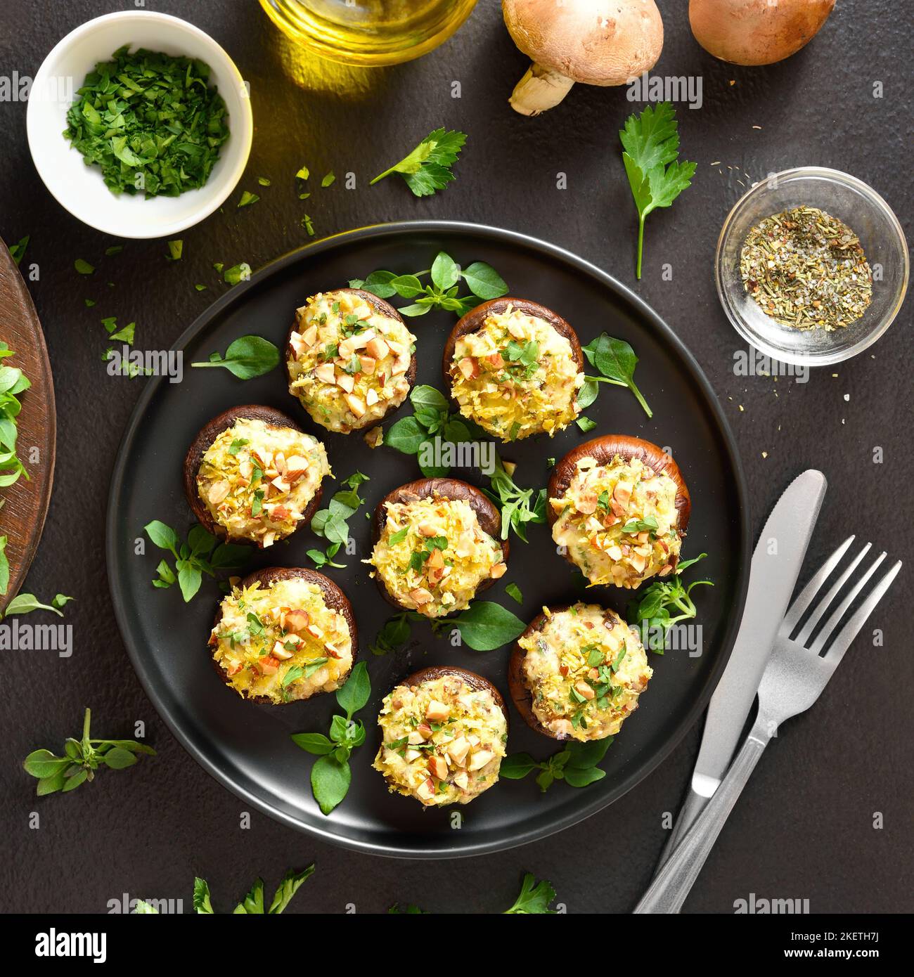 Stuffed mushrooms with cheese, bread crumbs and nuts on plate over dark ...