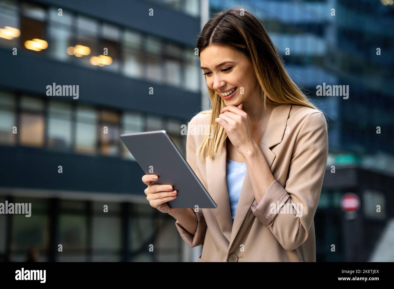 Portrait of successful woman using digital tablet in urban background ...