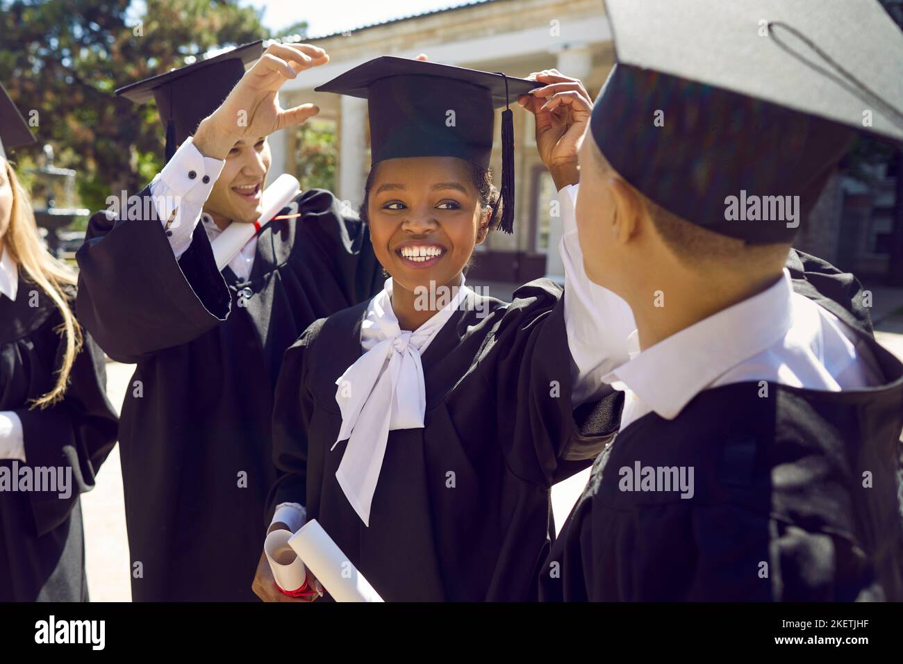 Happy diverse university students in academic caps having fun on their ...