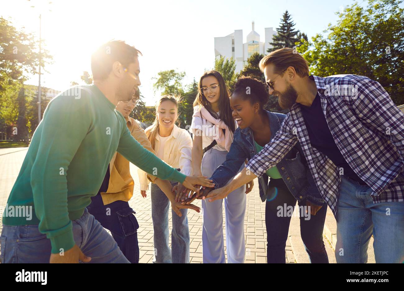 Team of happy young multiethnic friends stack their hands while having ...