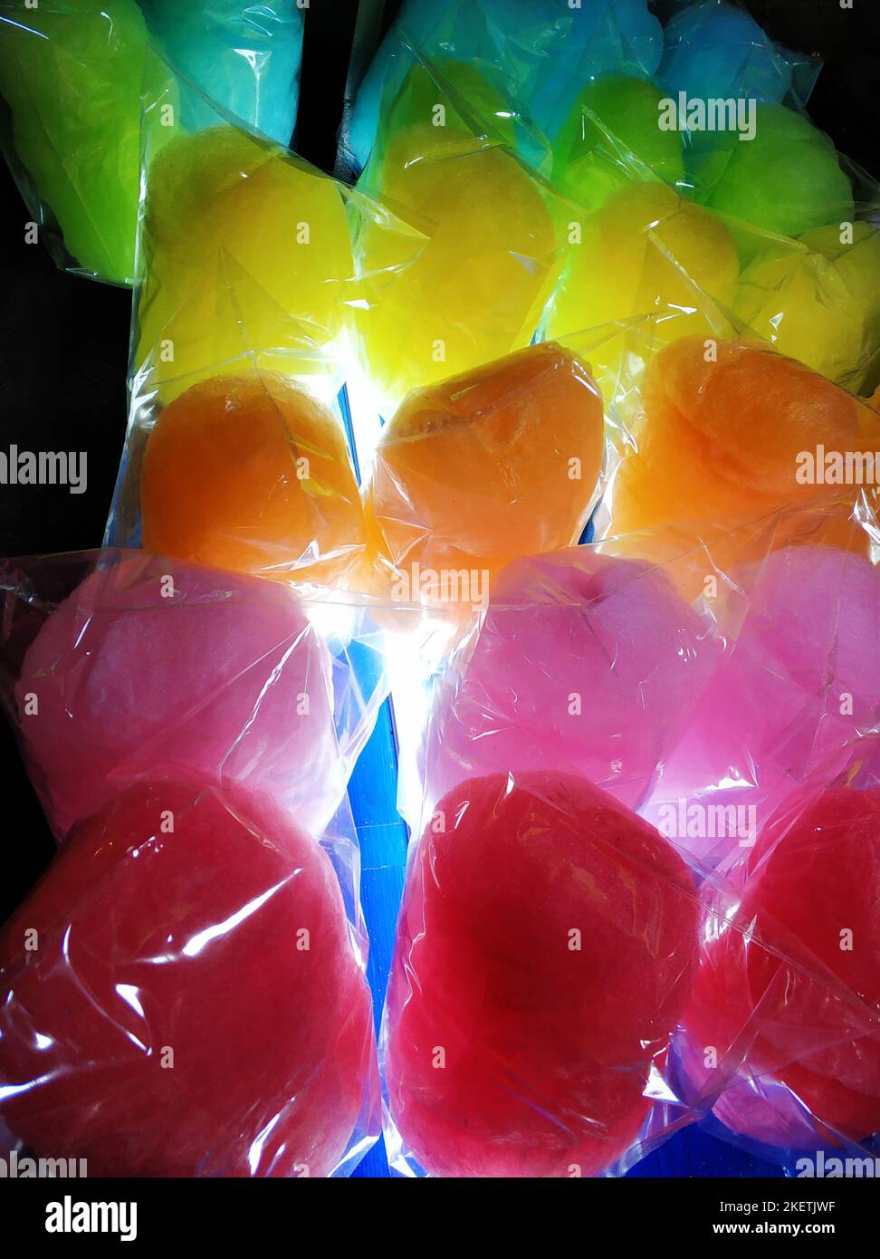 A counter selling colored cotton candy at a nighttime street food ...