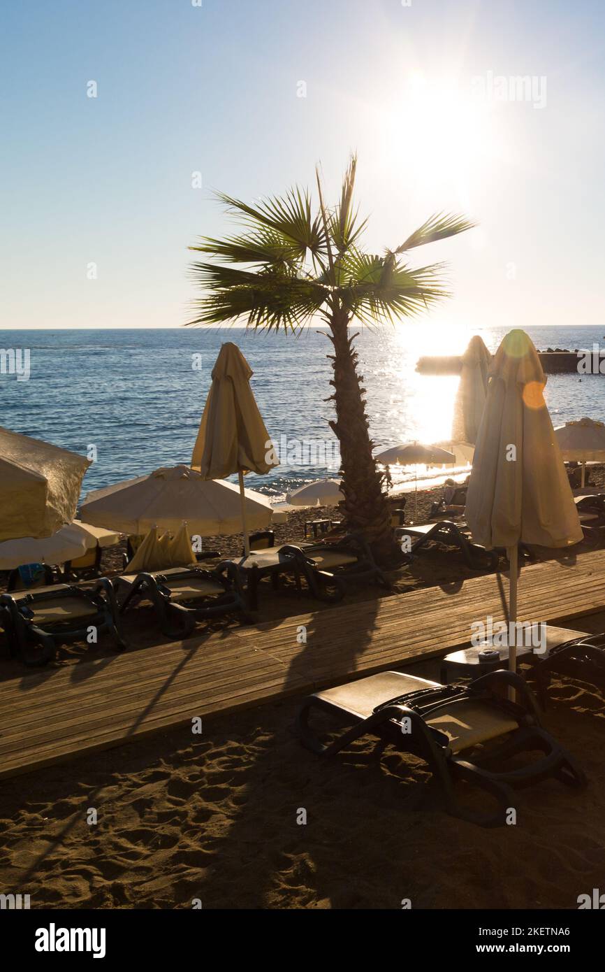 Sandy beach with umbrellas and sunbeds sunset Stock Photo - Alamy