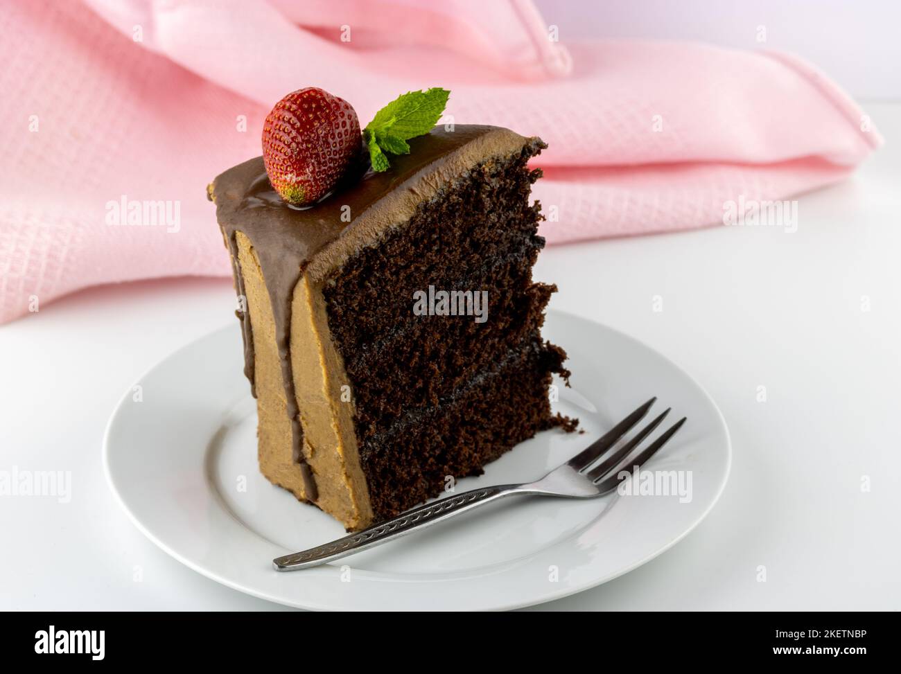 Slice of chocolate layer cake with fudge frosting and strawberry on ...