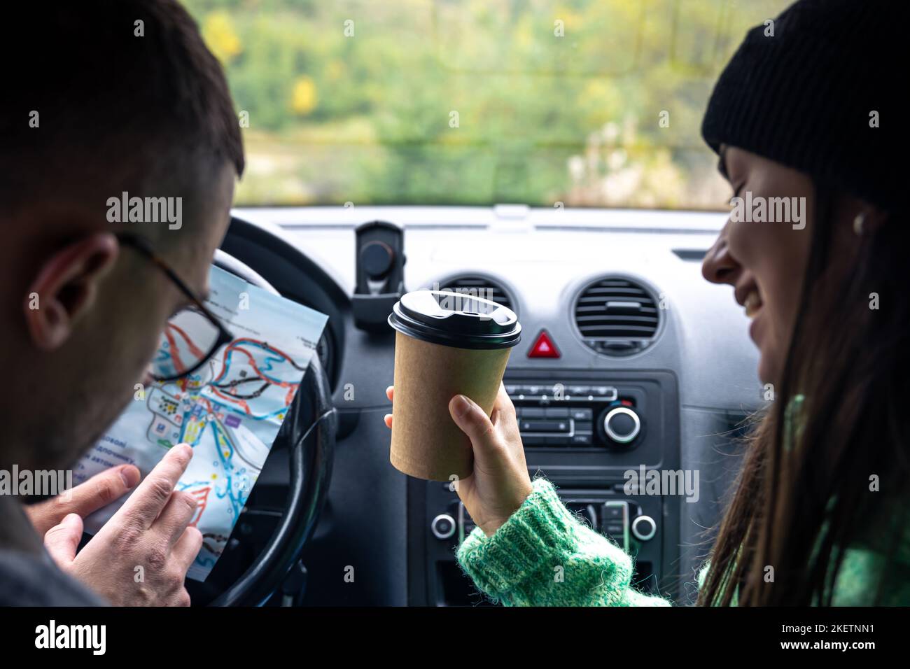 A man and lady holding and looking at paper map, sitting inside car ...