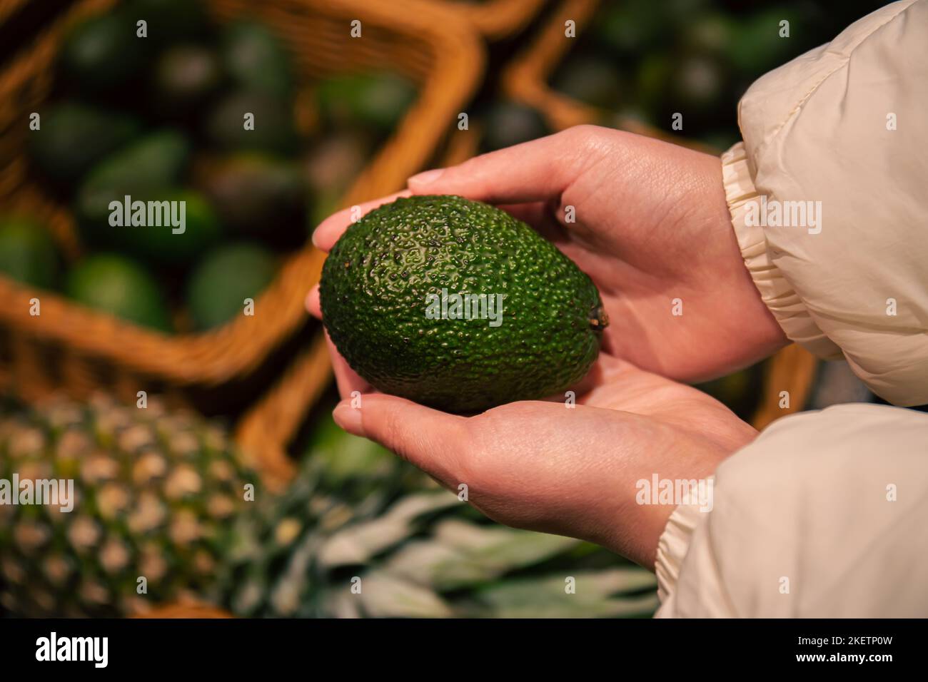 A woman chooses an avocado in a grocery store Stock Photo - Alamy