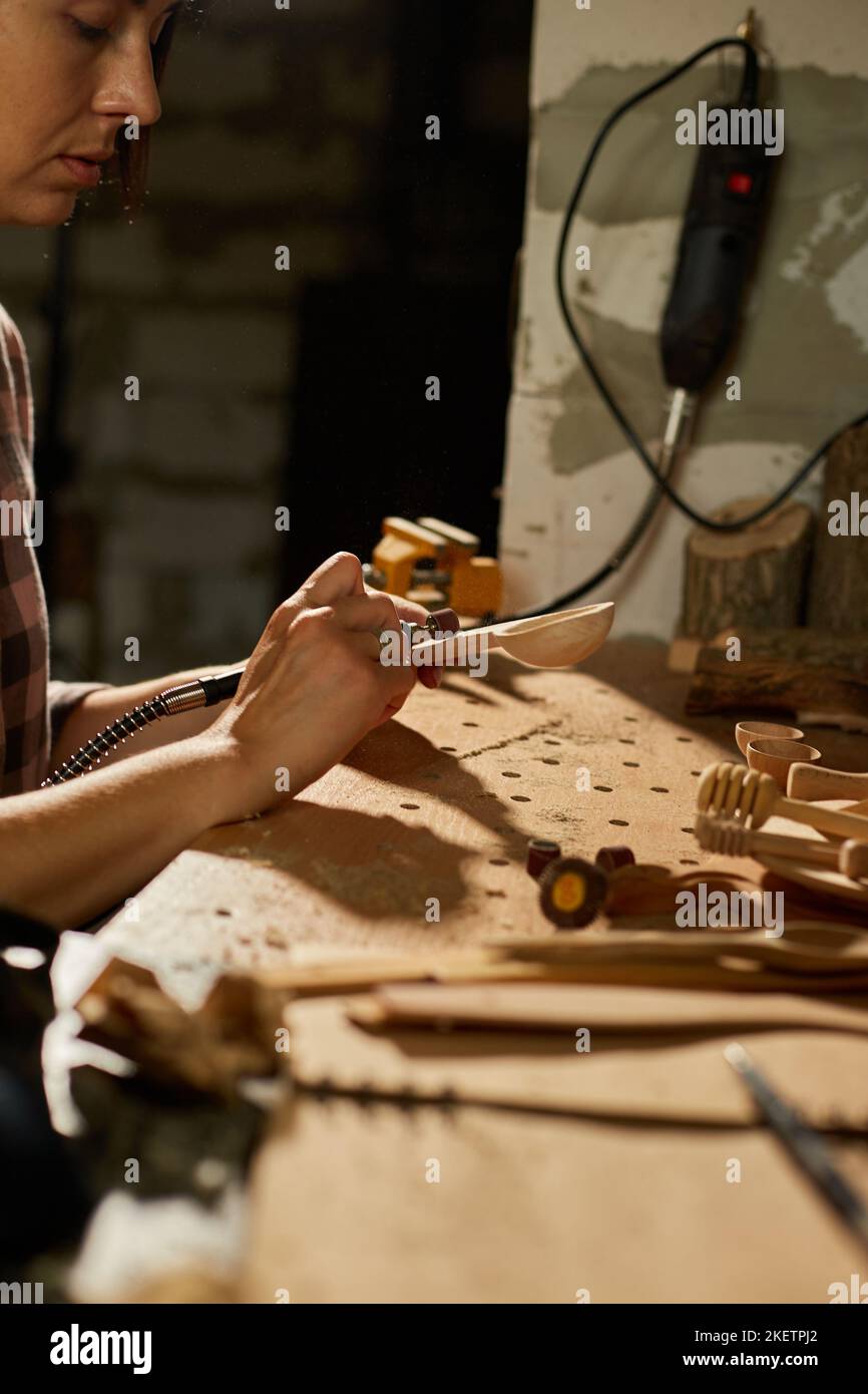 Female using power working tools graver for wooden utensils spoon ...
