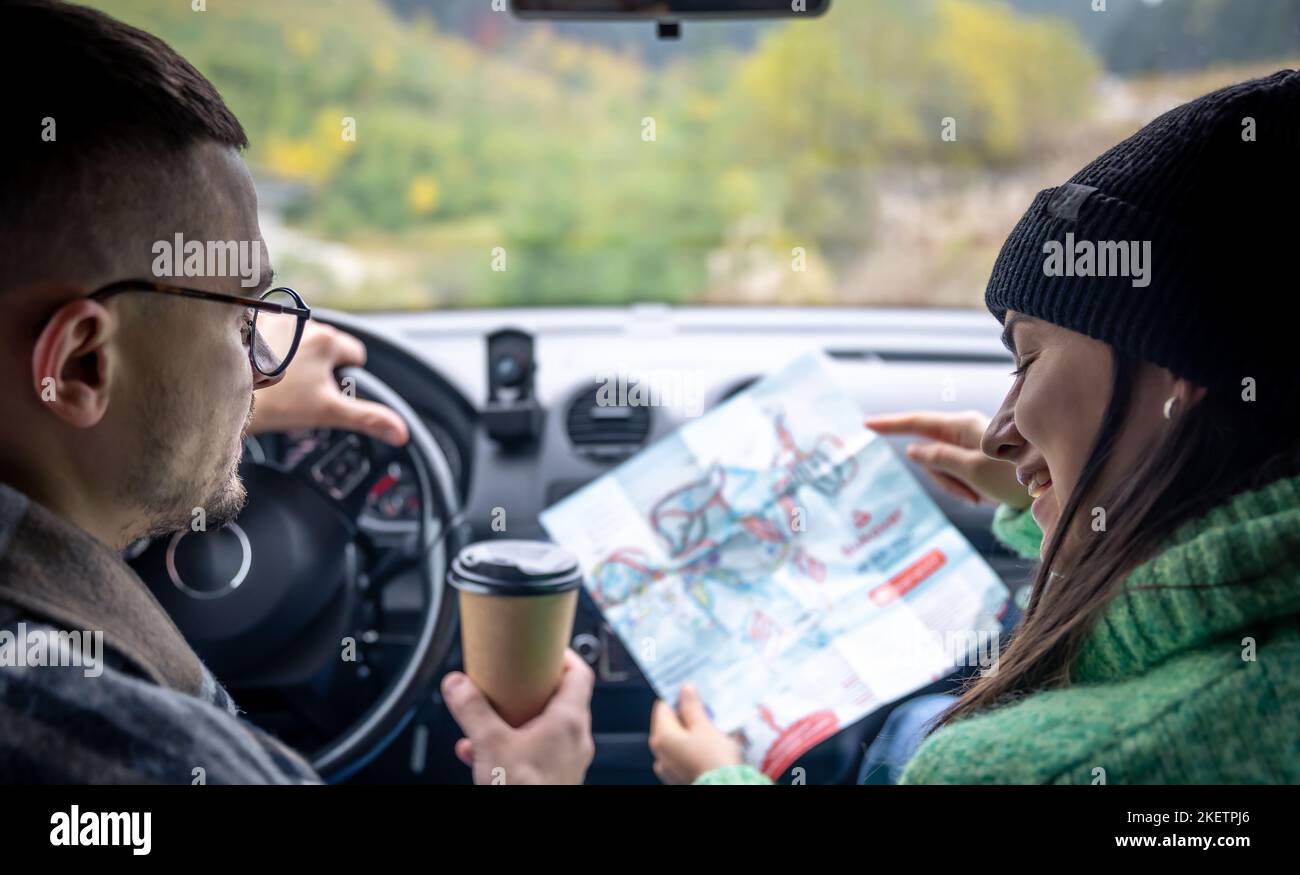 A man and lady holding and looking at paper map, sitting inside car ...