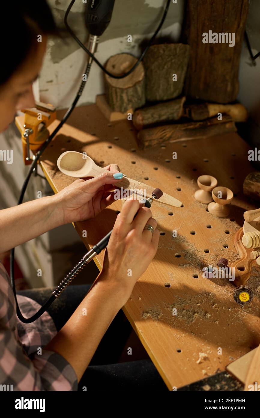 Female using power working tools graver for wooden utensils spoon ...
