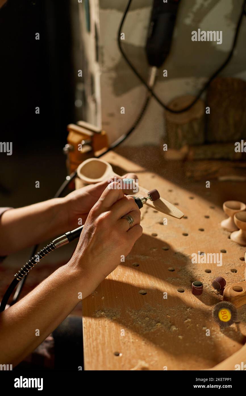 Female using power working tools graver for wooden utensils spoon ...
