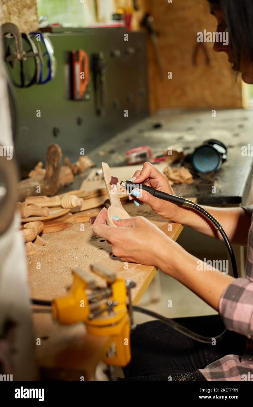 Female using power working tools graver for wooden utensils spoon ...