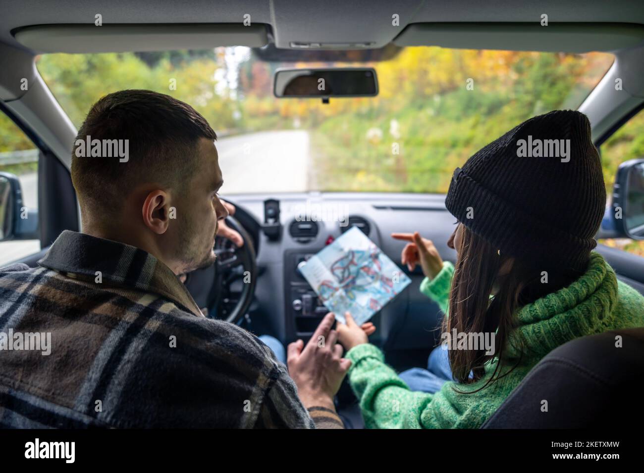 A man and lady holding and looking at paper map, sitting inside car ...
