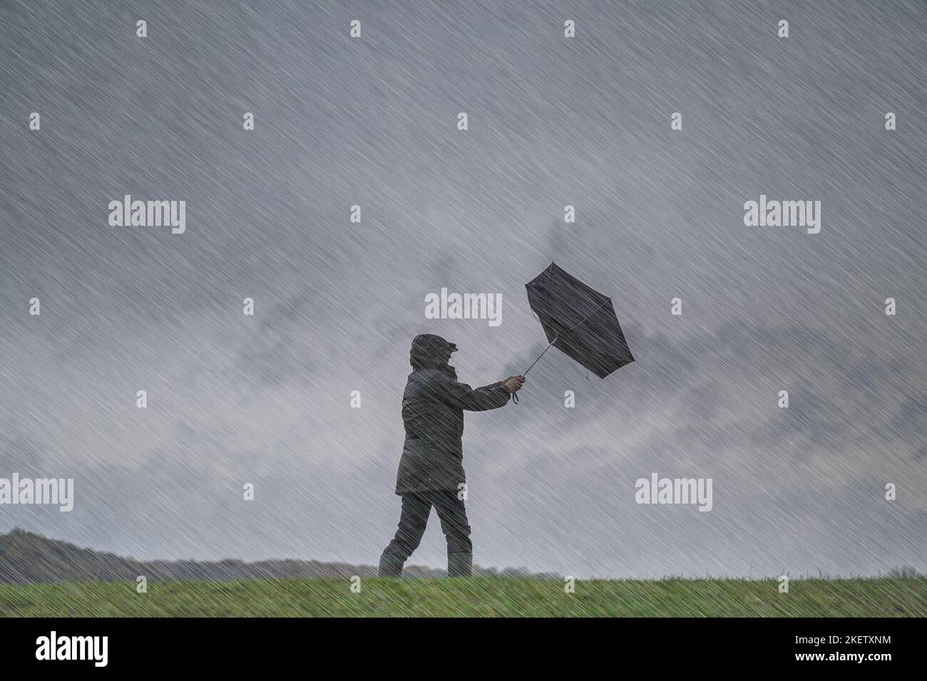 Isolated woman standing on a hillside in windy, wet and blustery UK ...