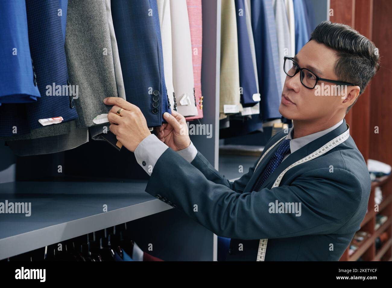 Salesman checking suits and jackets in his store Stock Photo - Alamy
