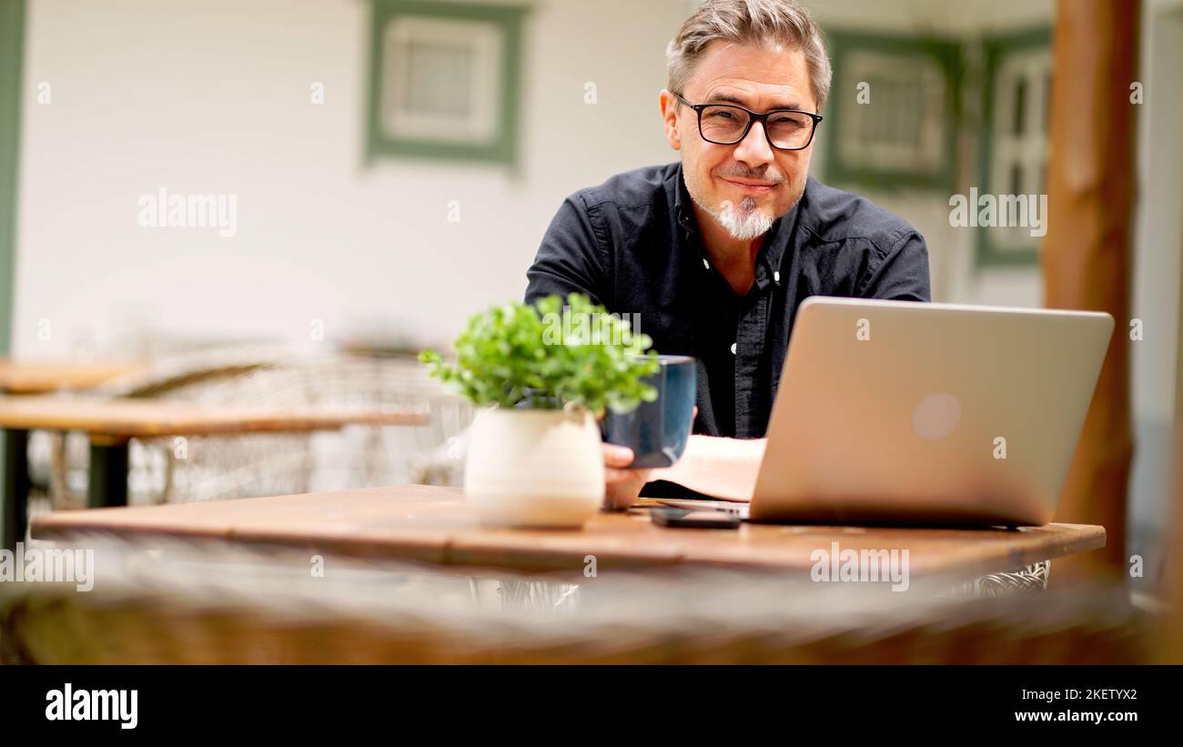 Middle aged man working with laptop computer at home outdoor i on ...