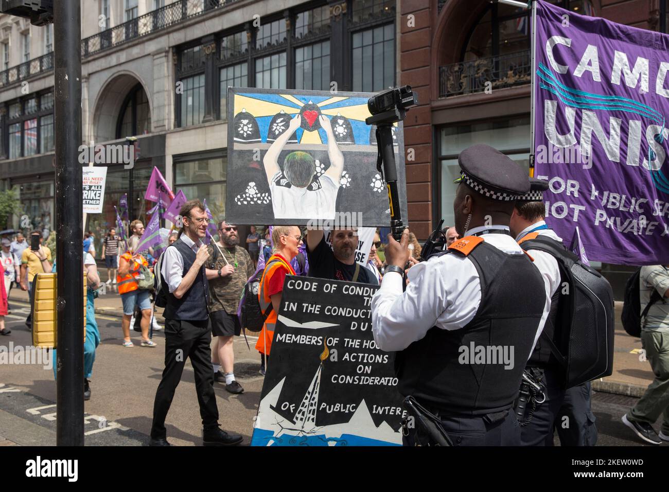 A police officer films as participants march during ‘We demand better ...