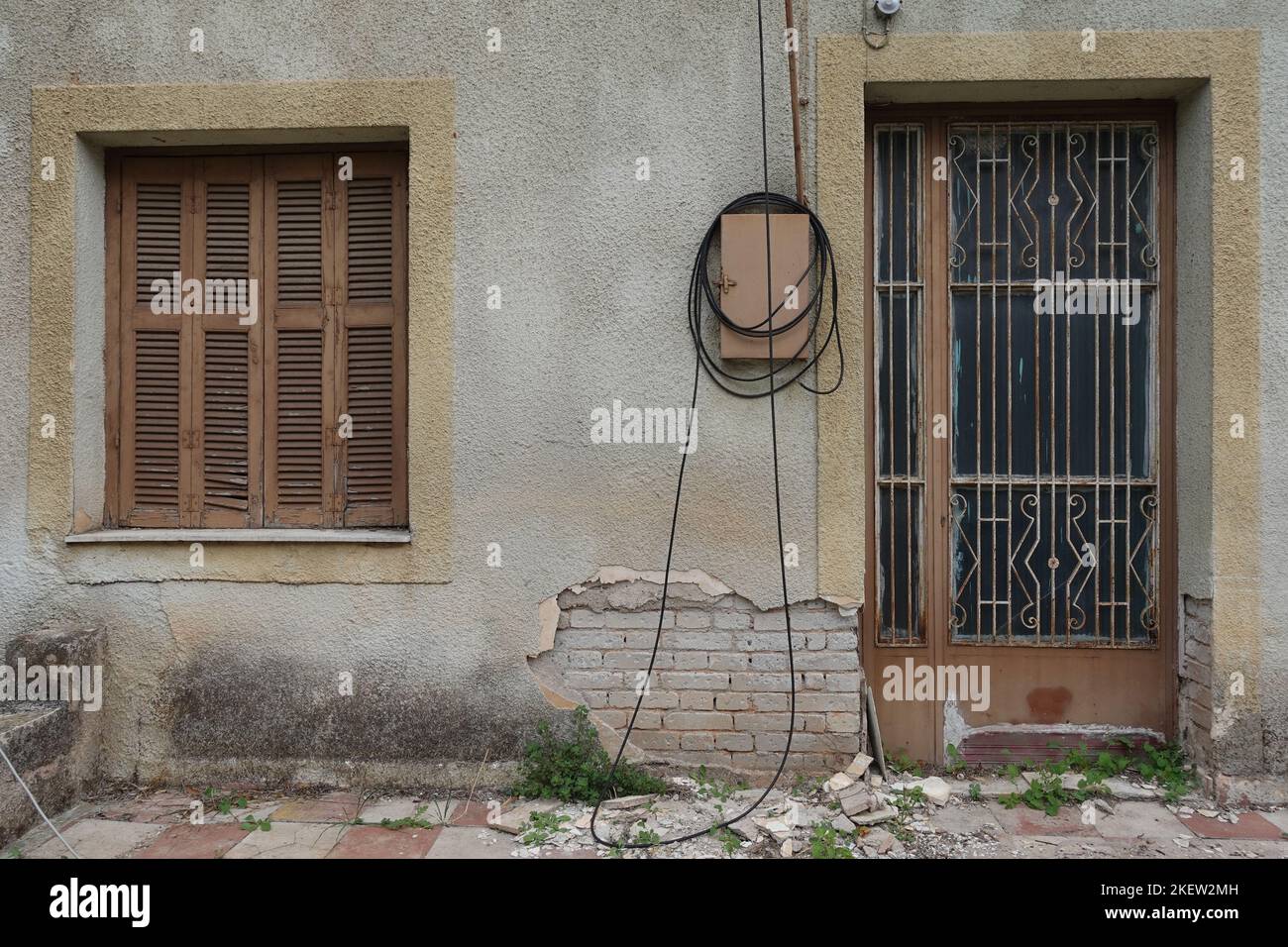 Front porch of an abandoned house. Old door crumbling wall and window ...
