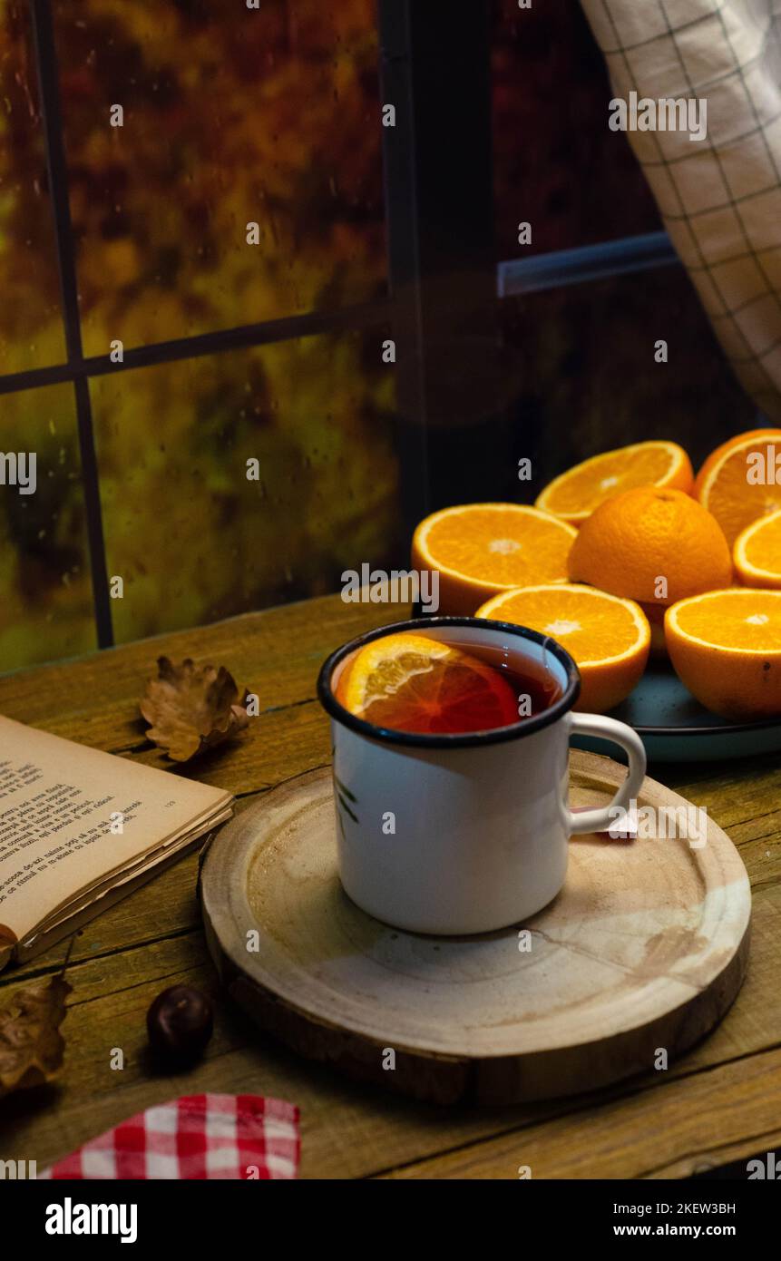 Cup of autumn tea with a book and yellow dry leaves near a window, copy ...