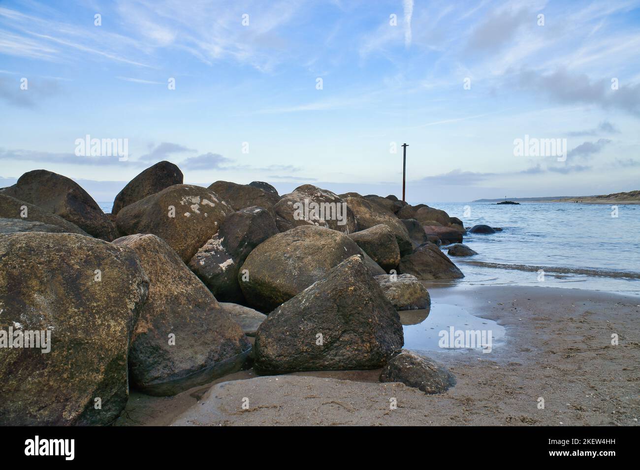 Stone groyne juts out into the water off the coast in Denmark. Sunny ...