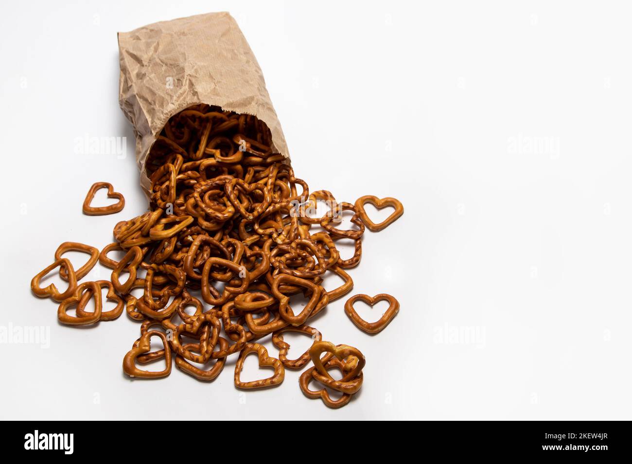 Heart-shaped salty pretzel snacks spilled from the paper bag on white ...