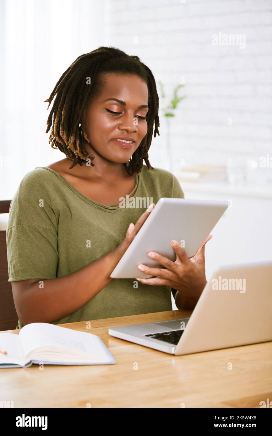 Portrait of cheerful freelancer working on tablet computer at home ...