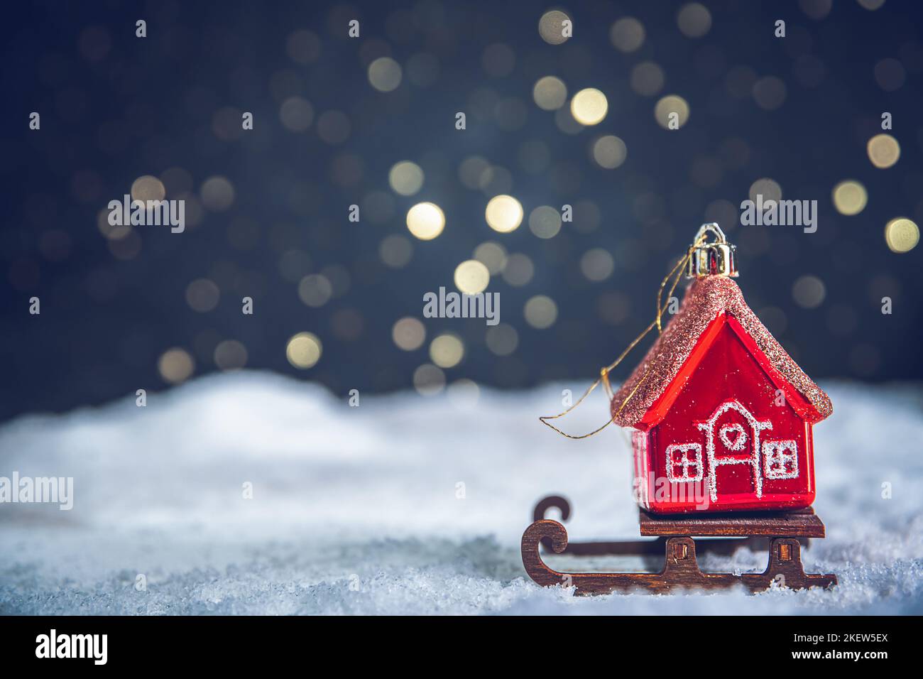 Christmas tree toy in the form of a red house on a sleigh in the snow ...